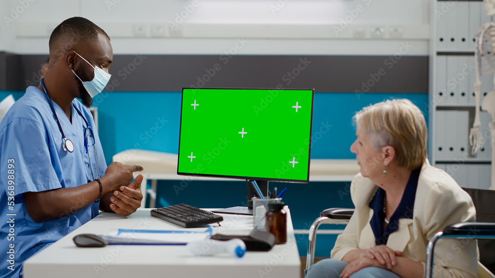 Assistant with face mask and woman in wheelchair using greenscreen ...