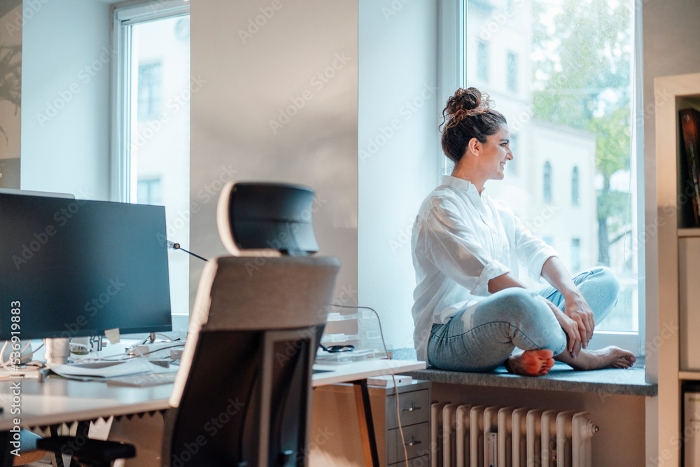 Businesswoman looking through window in office Stock Photo | Adobe Stock