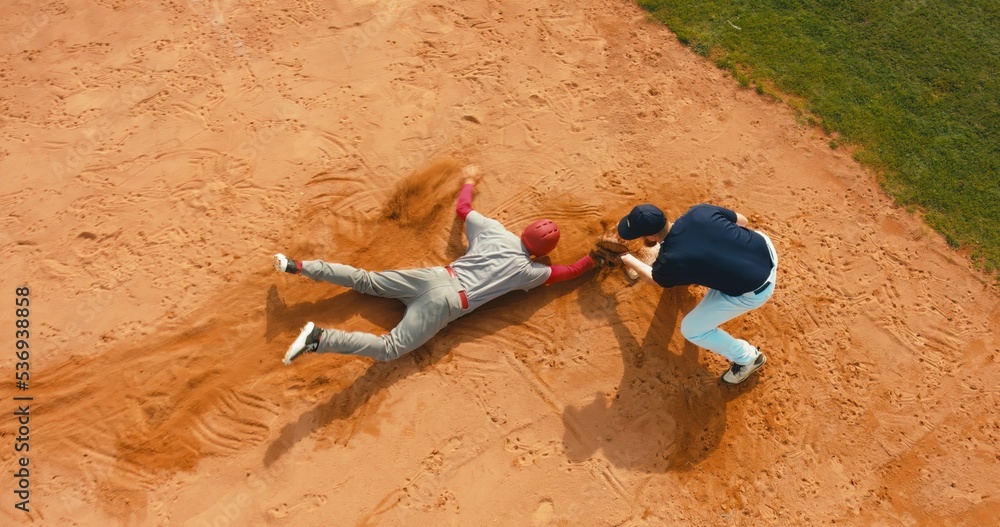 OVERHEAD Base runner attempts to touch a base during a baseball game ...