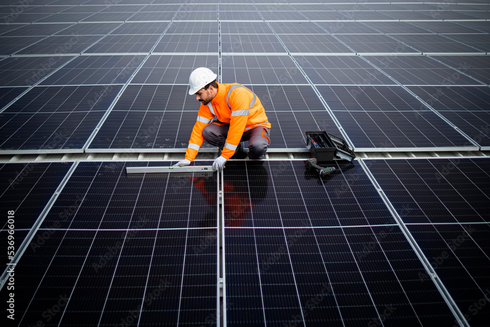 Professional worker checking level and installing solar panel modules ...