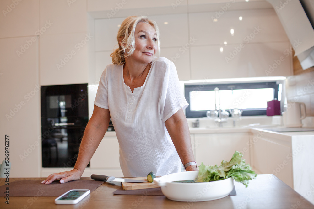 Middle- aged woman cooking in the kitchen at home. 60s year old woman ...