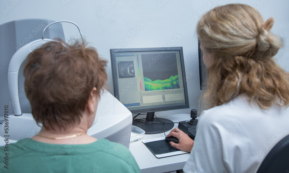 an elderly woman on a CT scanner does a retinal tomography in the ...