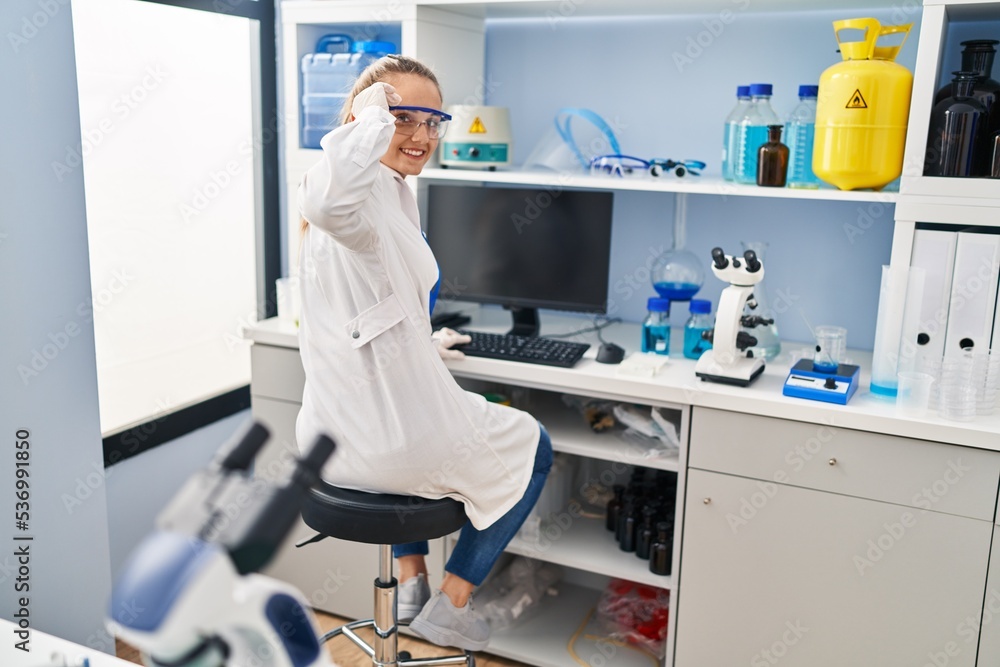 Young blonde woman wearing scientist uniform using computer working at ...