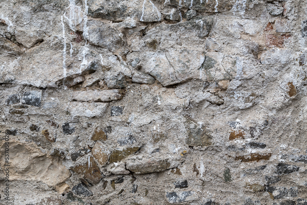 Messy stone and concrete wall with white paint dripping down from the ...