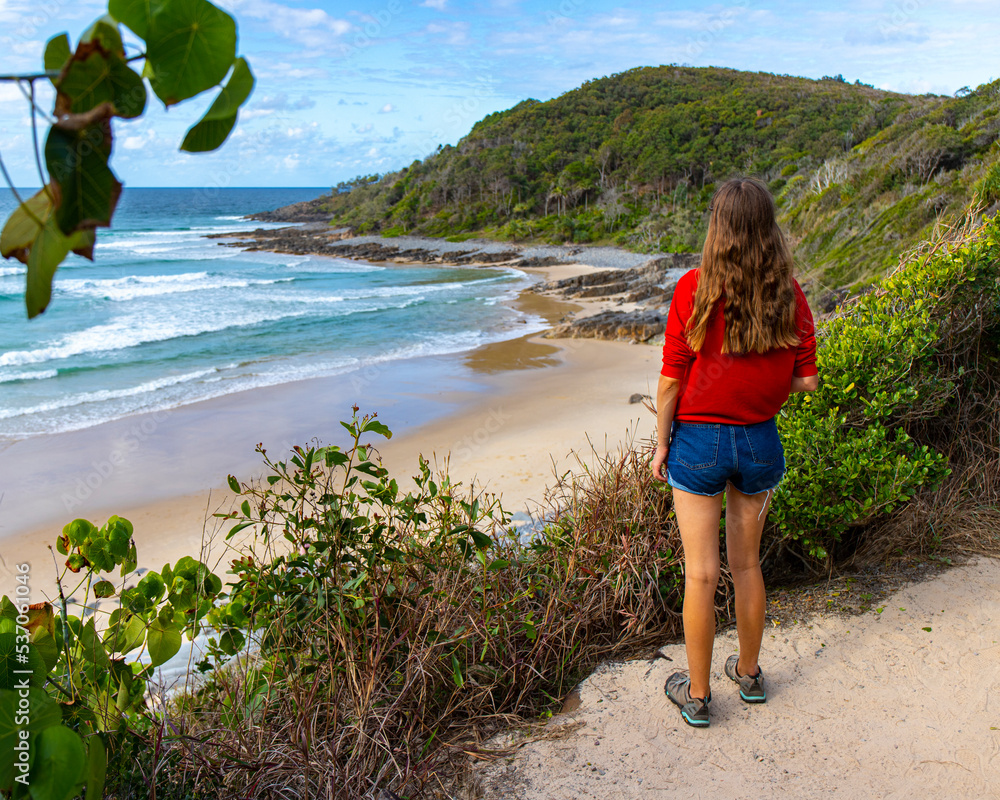 long-haired girl stands on a hill overlooking surfers' beach in noosa ...