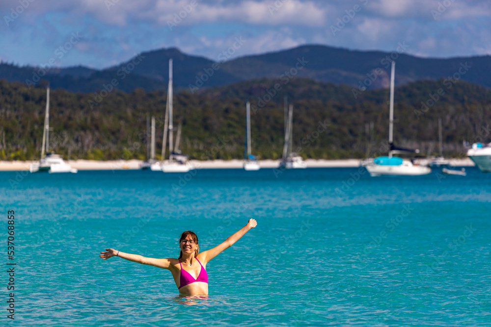 Foto de A beautiful girl in a bikini enjoys a dip in the turquoise water on whitehaven beach ...