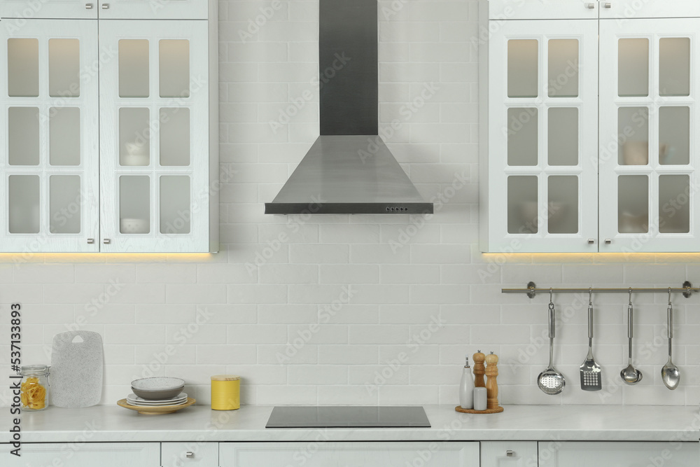 Elegant kitchen interior with modern range hood over cooktop and ...
