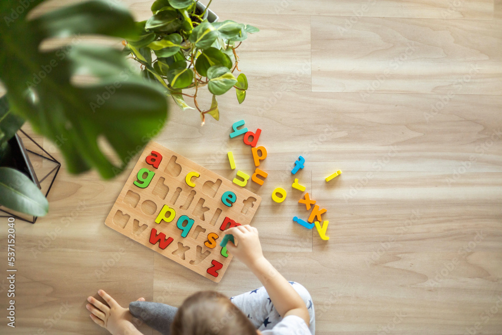 Male kid playing with wooden eco friendly alphabet letters board on ...