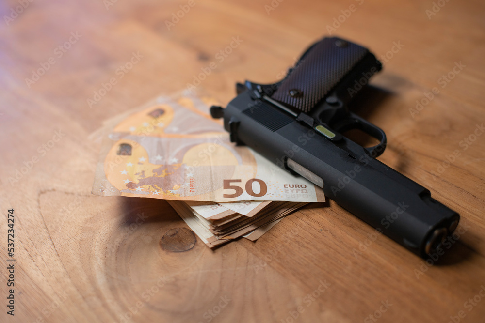 pistolet posé sur une table à côté d'une liasse de billets de banque de ...