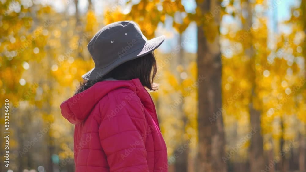 Portrait of cheerful Indian female wearing cap and looking at warm fall ...