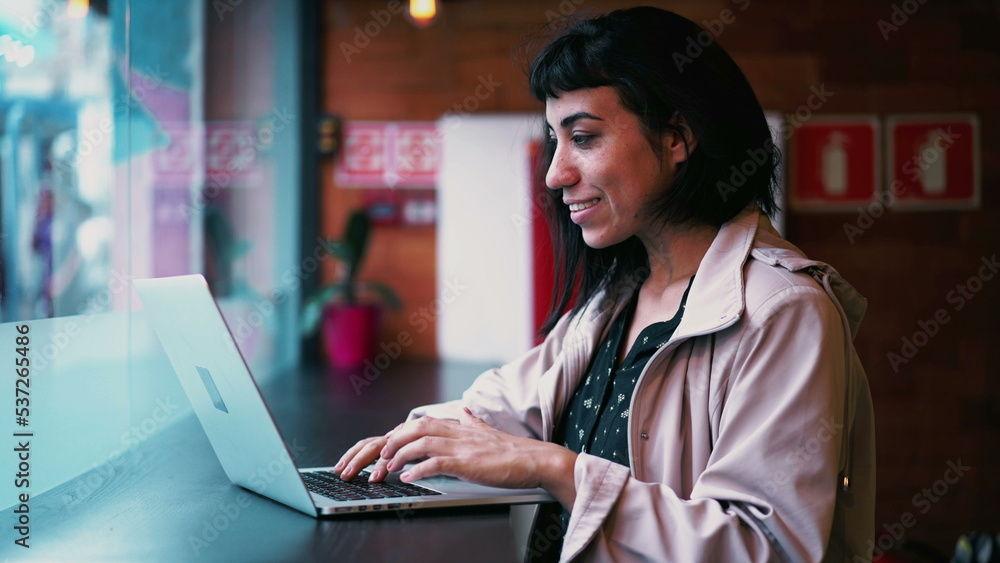 South American happy young woman working in front of laptop at cafe ...