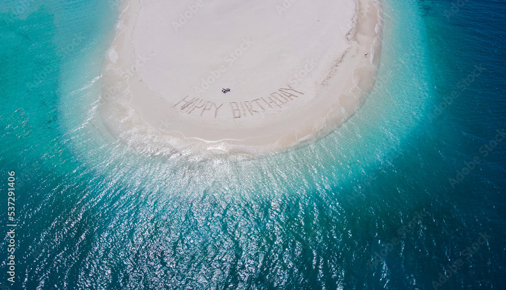 Hand written Happy Birthday on the sandy beach by the ocean on a desert ...