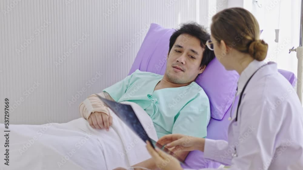 Caucasian female doctor explaining brain X-ray film to Asian male ...