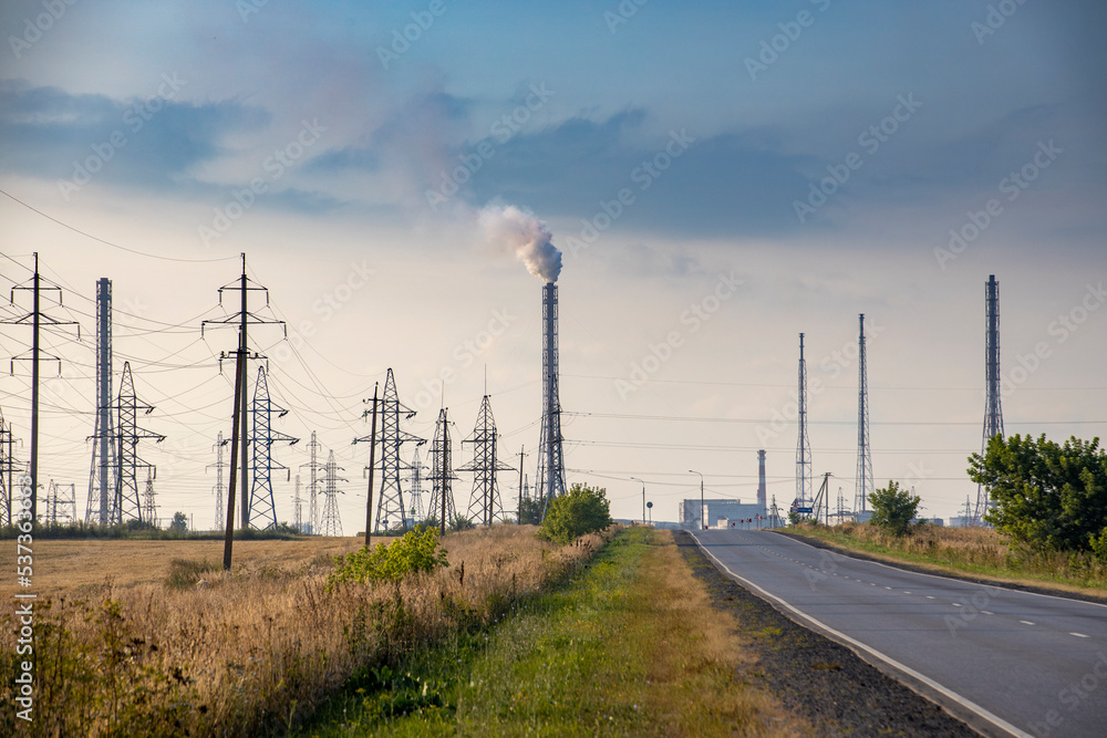 Power lines along the road. Asphalt road and high voltage power towers ...