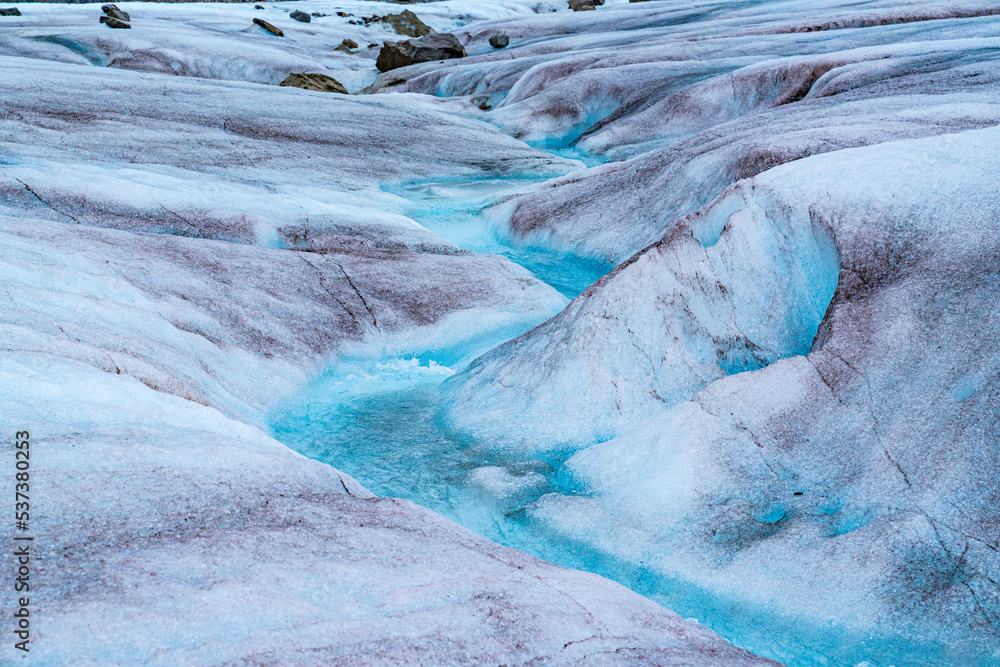 Melting glacier ice in the Mendenhall Glacier in Alaska forms a winding stream of crystal clear ...