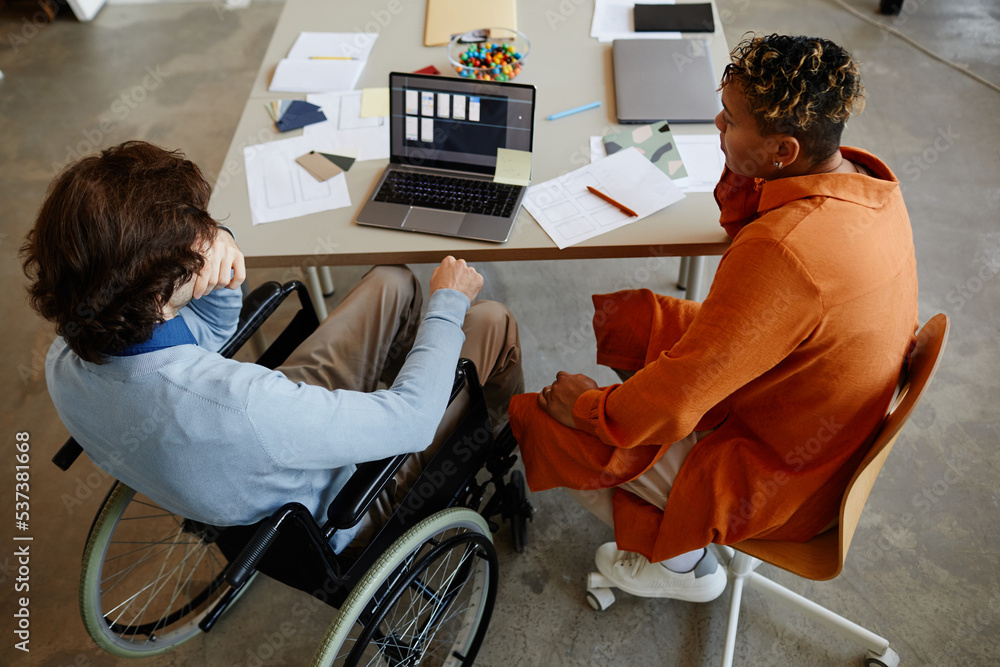 Top view of young man with disability talking to colleague or manager ...