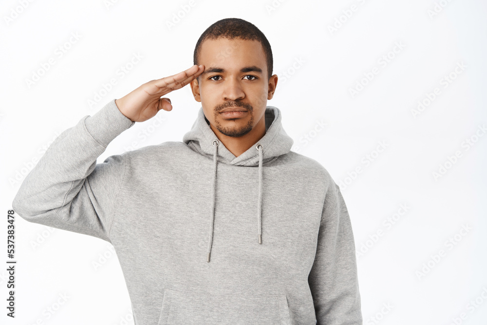 Image of young man saluting, holding hand near forehead, army greeting ...