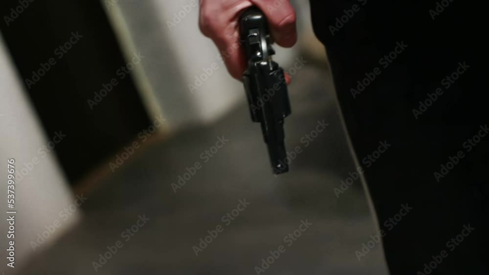 Close-up Man lowers his revolver pistol to the foot in black pants ...
