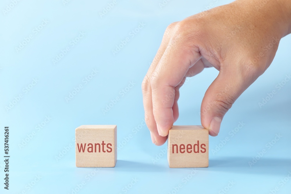 Choose between wants versus needs concept. Hand choosing wooden blocks ...