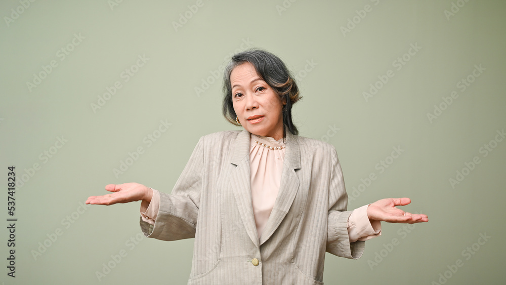Uncertain and confused 60s aged asian woman shrugging her shoulders ...