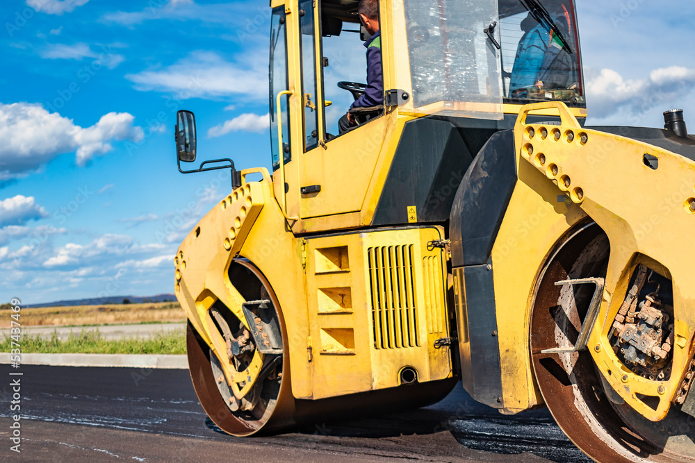 Vibratory road roller lays asphalt on a new road under construction ...