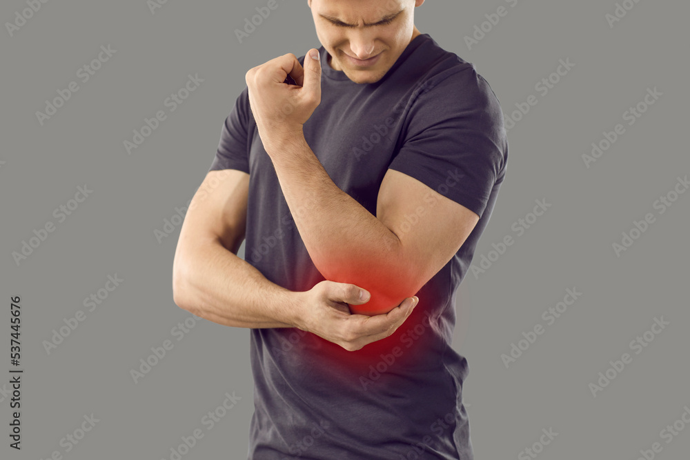 Young man who suffers from pain due to stiff elbow, bruise, or ...