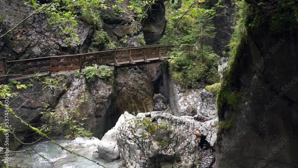 wooden bridge through a gorge with fresh water floating in a river ...