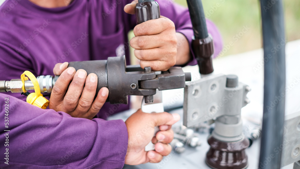 Two electrician builder workers installing high-voltage cable.Hydraulic ...