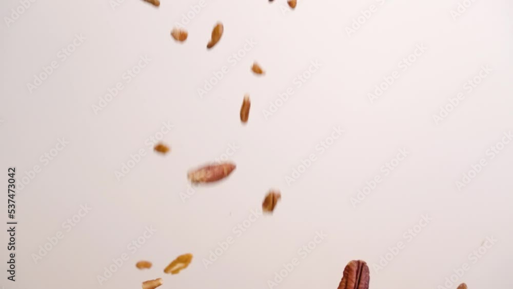 Pecans raining down and bouncing on white backdrop, whole and half nuts ...