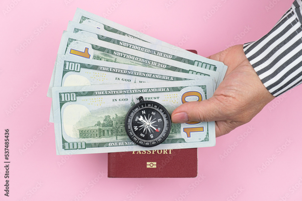 Human hand holds manual travel compass and cash dollars over a ...