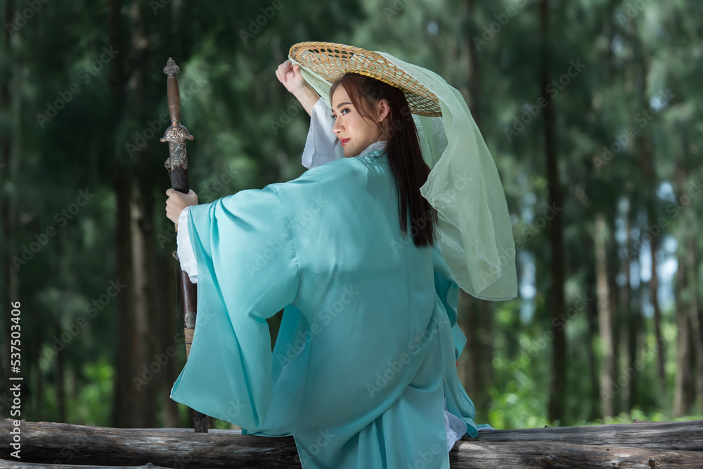 Portrait woman in a Chinese costume with a sword in the forest. Chinese ...