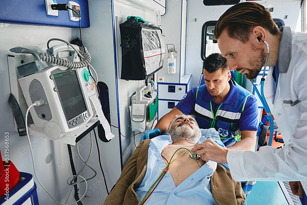 Doctor listening to heartbeat of injured patient connected to ECG ...