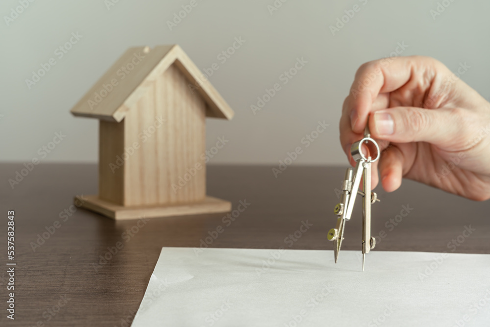 Architect drawing with the compass on a white paper the plans of a new ...