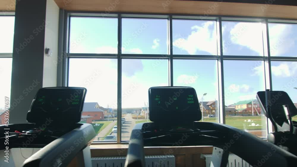 Contemporary treadmills stand near large window in sports club gym ...