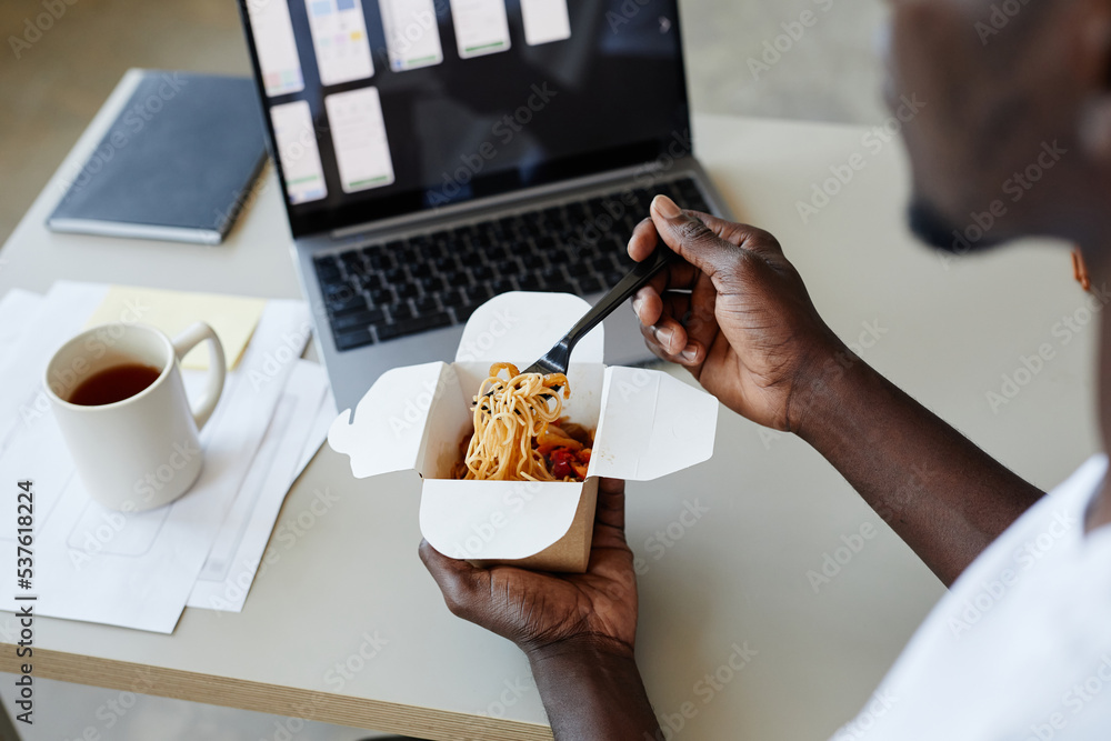 High angle close up of young black man eating takeout noodles at ...