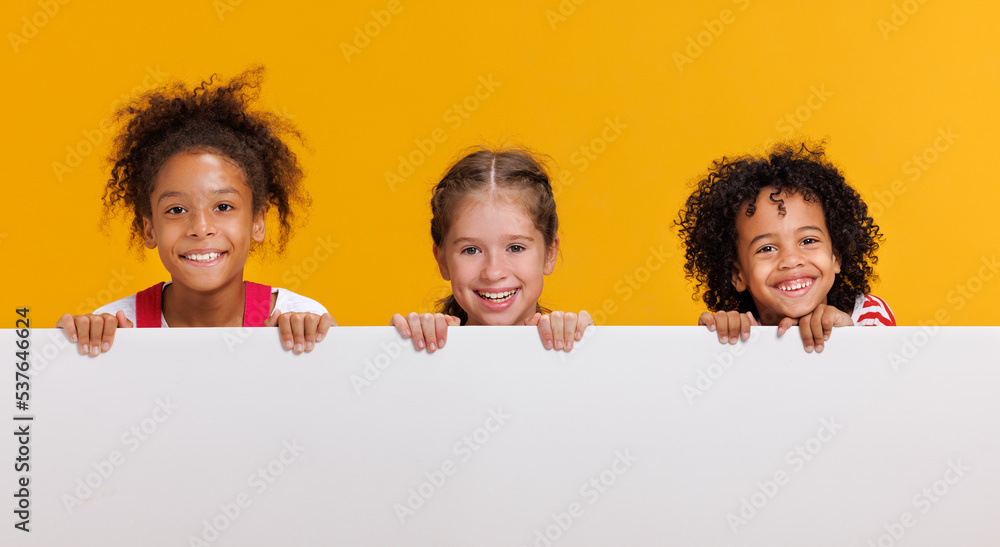 Group of cheerful happy multinational children with blank white poster ...
