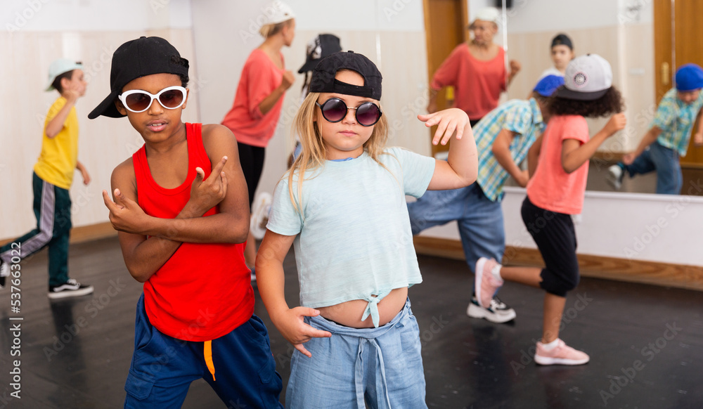 Tween blonde girl and boy in caps and sunglasses dancing hip-hop in ...