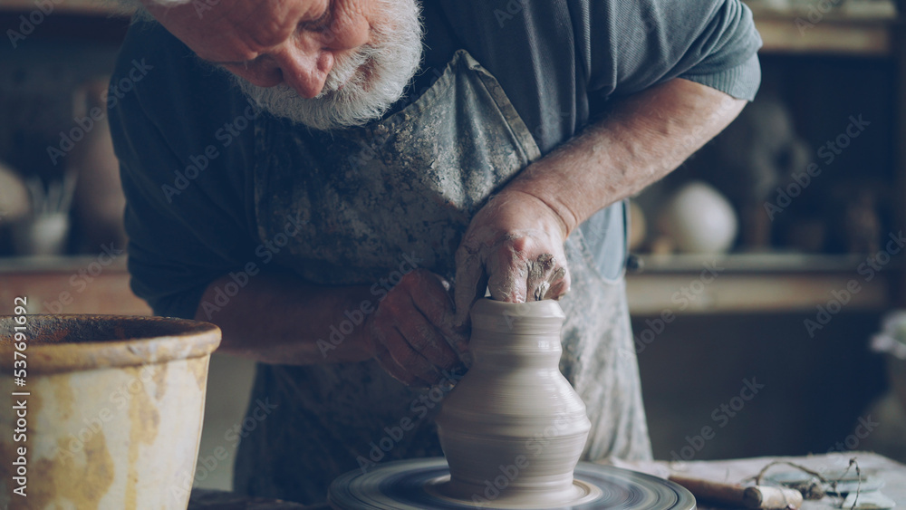 professional male potter creating jar from brown clay in workplace ...