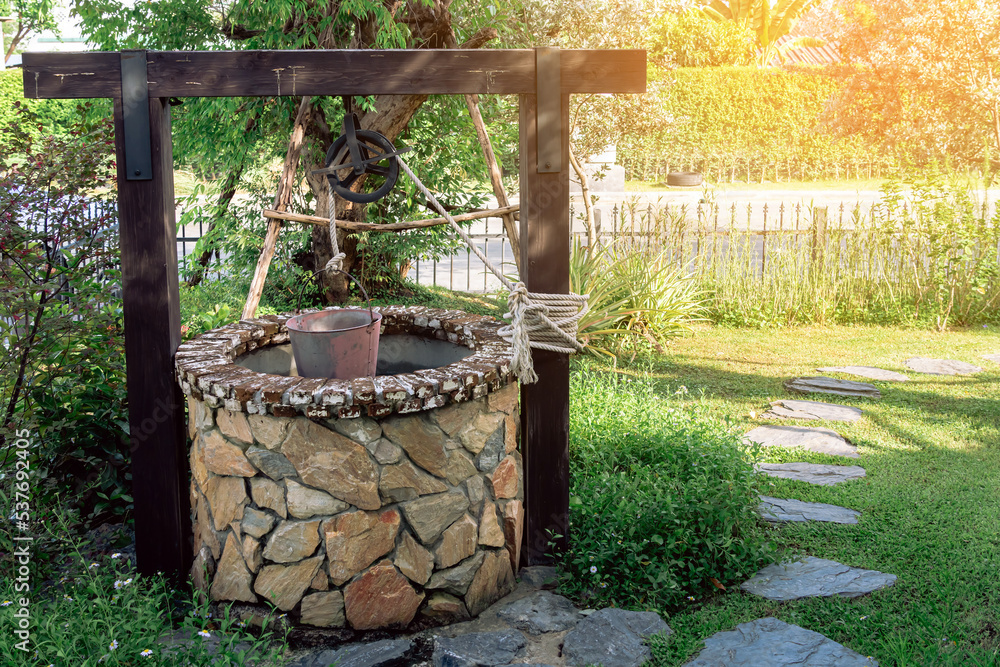 Beautiful artesian well made by stones and wheel pulley with metal ...
