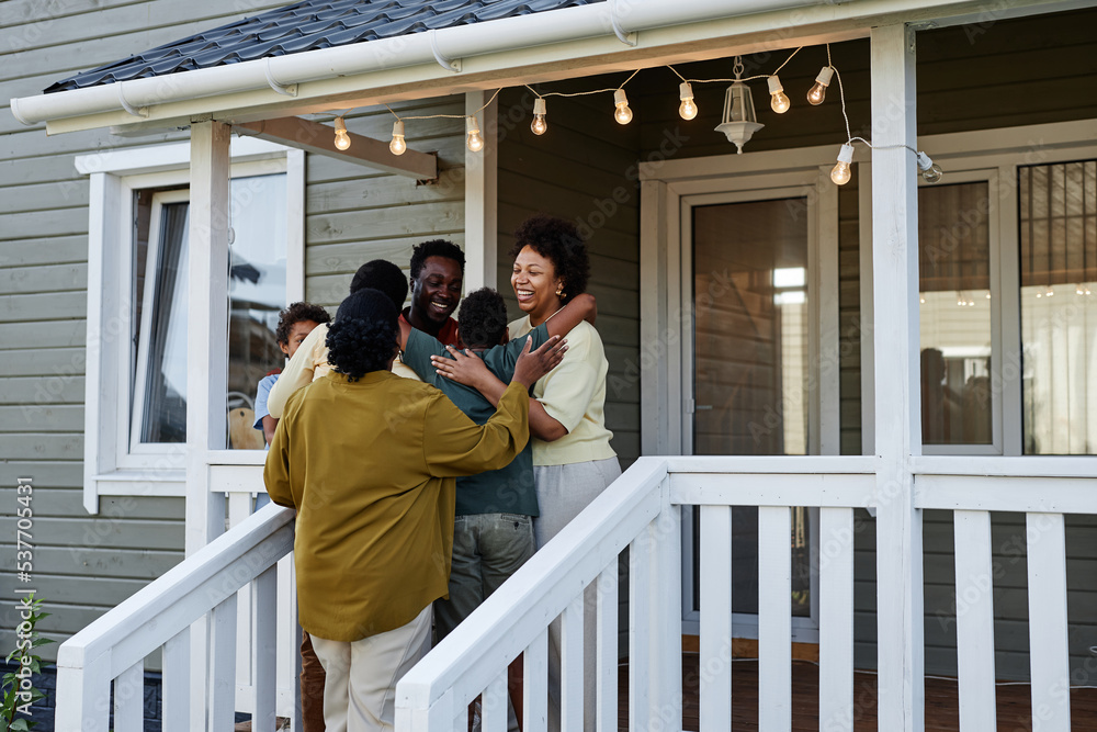 Portrait of happy black family embracing while standing on porch of new ...