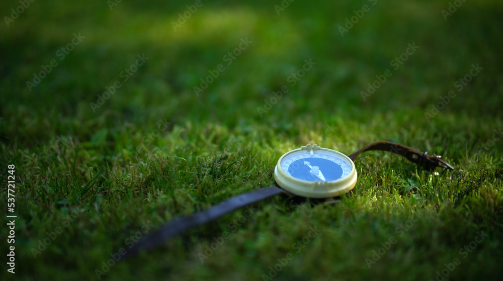 An old wrist compass is lying on the green grass.Orientation on the ...