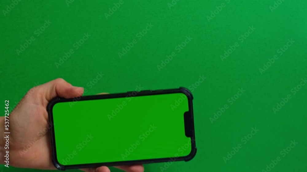 Hands holding cell phone with green screen on green background. Chroma ...