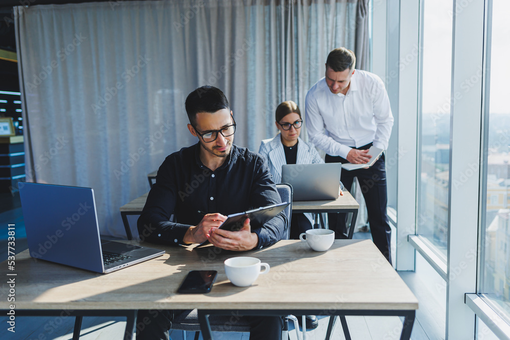Diverse international business people working on a project at the table using laptops ...