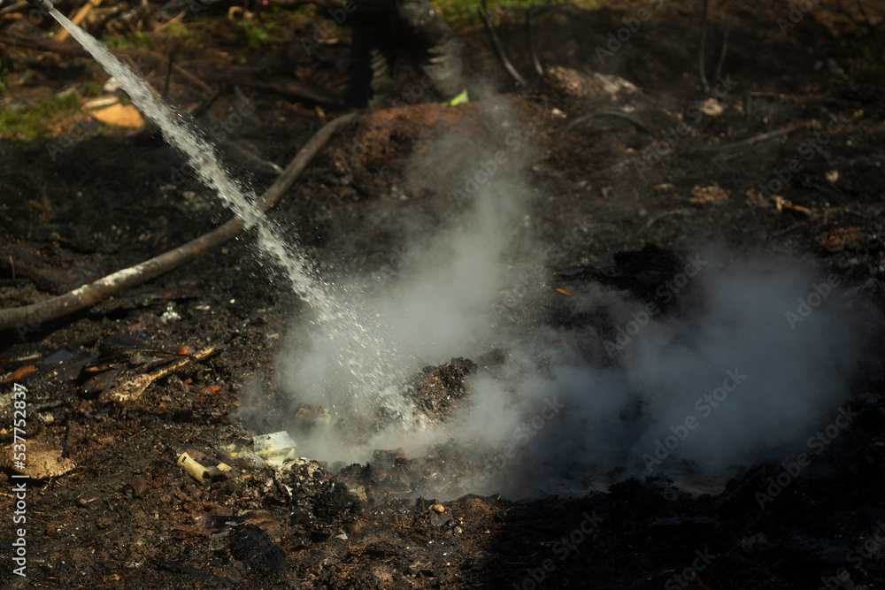 Jet of water extinguishes earth, Steam from ground. Putting out fire ...