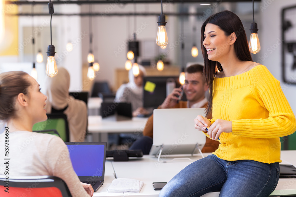 Creative team of young individuals working on desktop and laptop ...