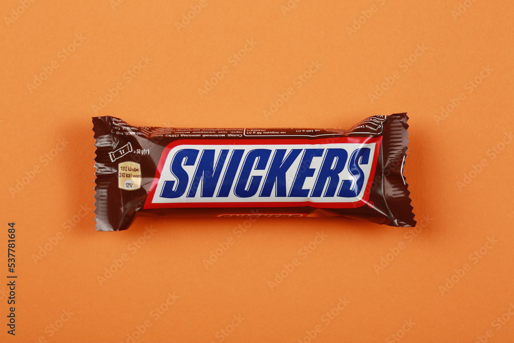 Snickers chocolate bar on an orange background, top view, flat lay ...