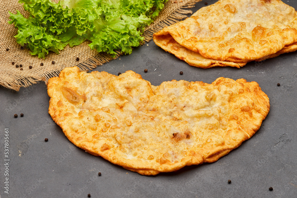 Cheburek - fried pie with meat and onions on dark stone background ...