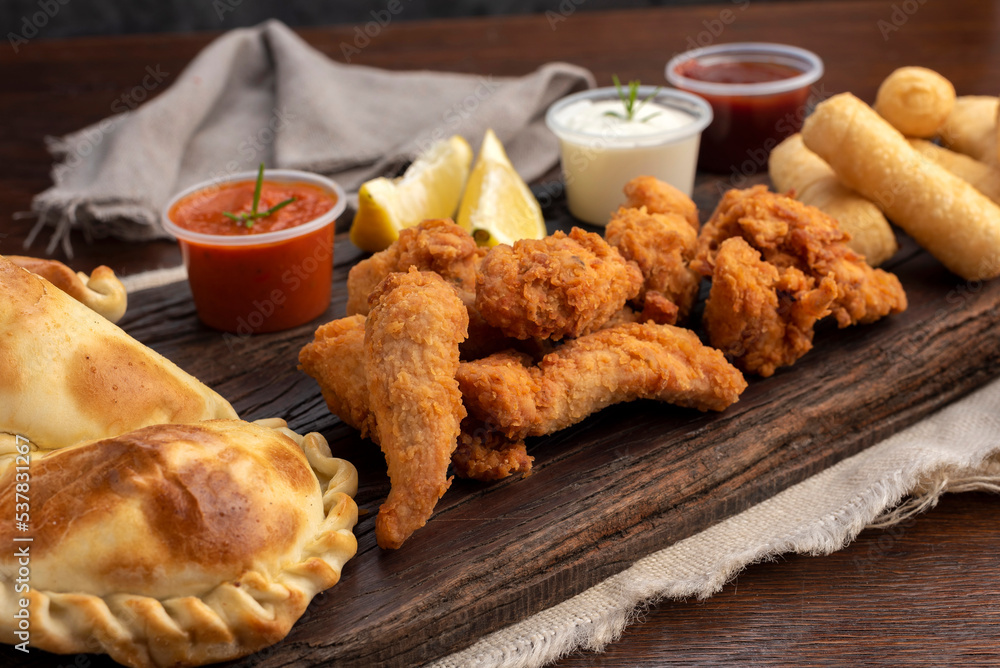 Picada board with nugget empanadas and tequeños with lemon slices and ...