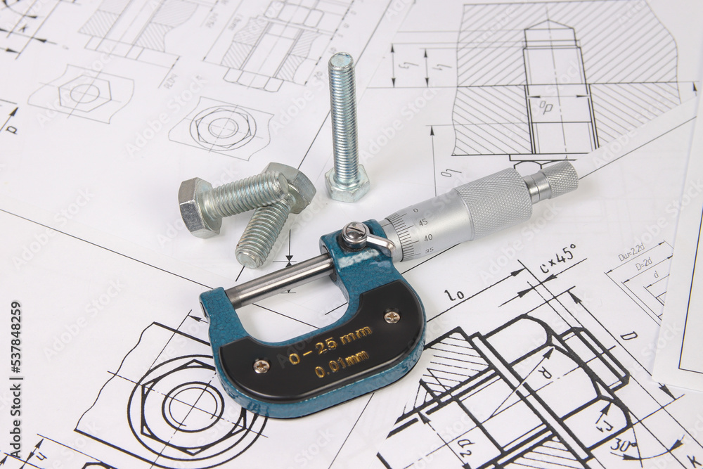 micrometer and bolts on a background of engineering drawings. Science ...