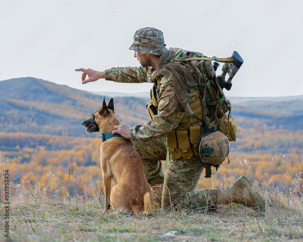 Foto de Soldier with a dog. Infantryman shows his dog the direction and ...